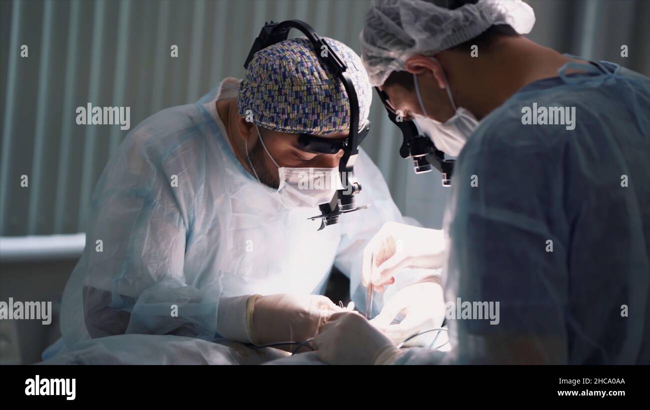 Medical team performing operation. Close up of faces of surgeons at ...