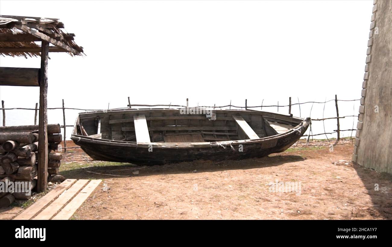 Old dilapidated black wooden boat with a one-storey house, a well and a ...
