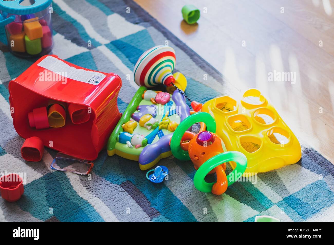 Mix of colorful toys laying on a carpeted floor Stock Photo - Alamy