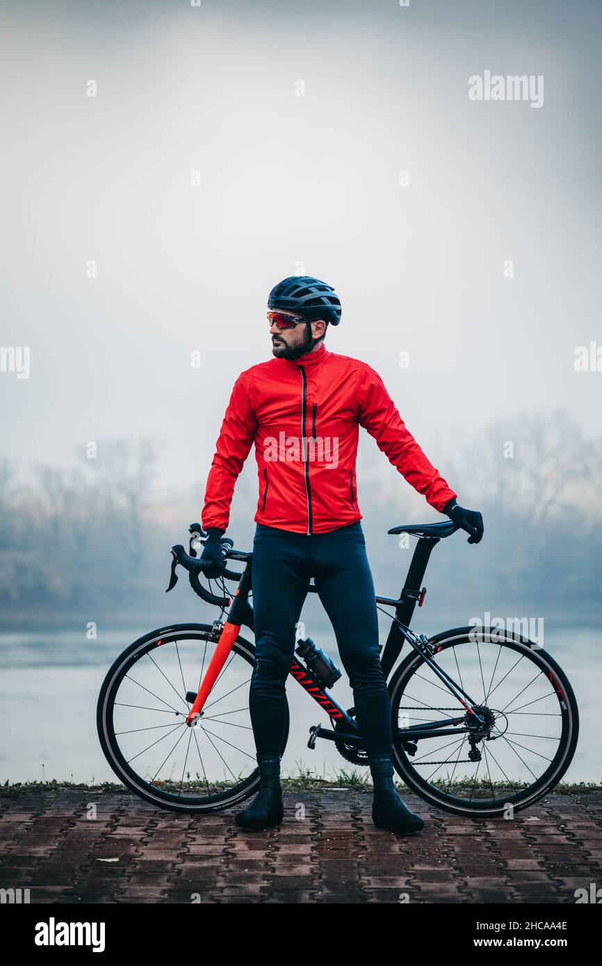 Young cool male cyclist in red sportswear posing with his bicycle by ...