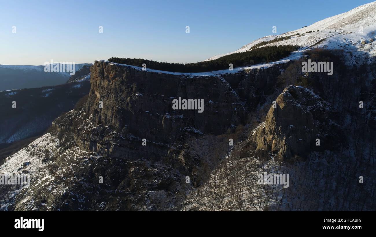 The slope of the high rock massif covered with pine trees on blue clear ...
