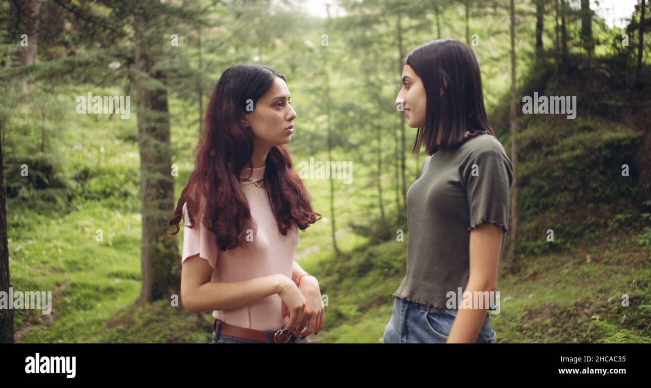 Two Indian female standing in the forest talking to each other with ...