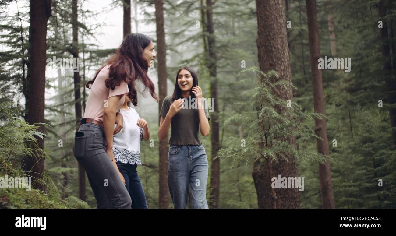 Three Indian females having fun and laughing in the forest with blurred ...
