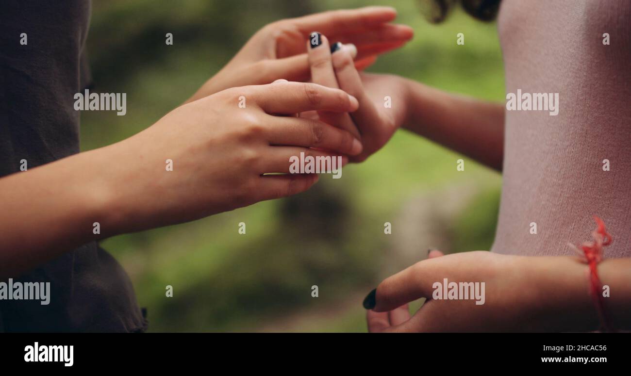 Closeup of female hands holding each other with background of green ...