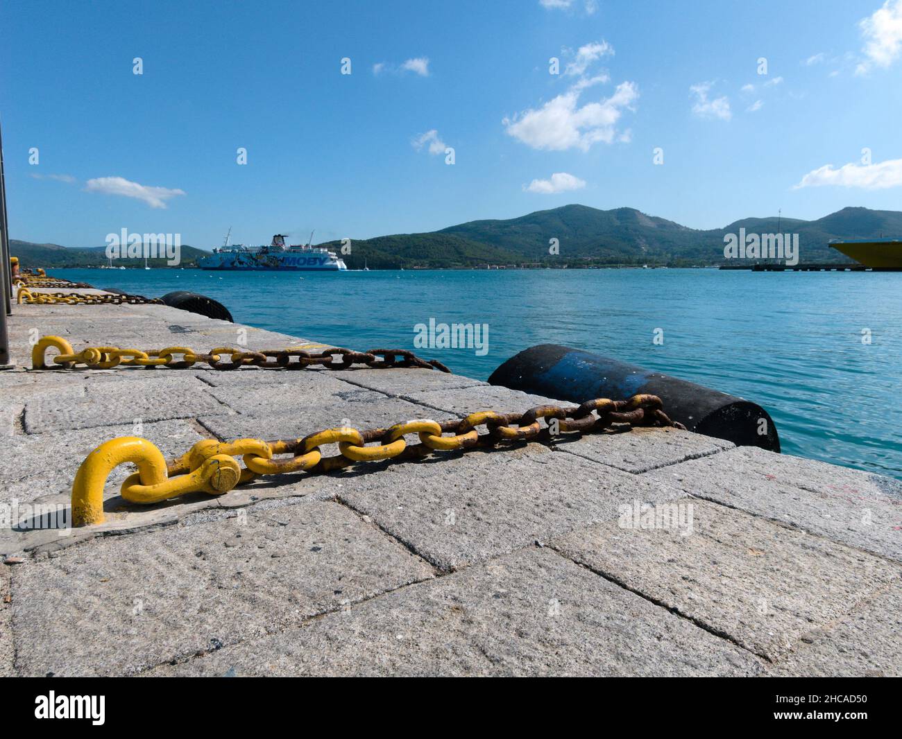 Yellow anchor chain harbor with marine fenders with calm sea against ...