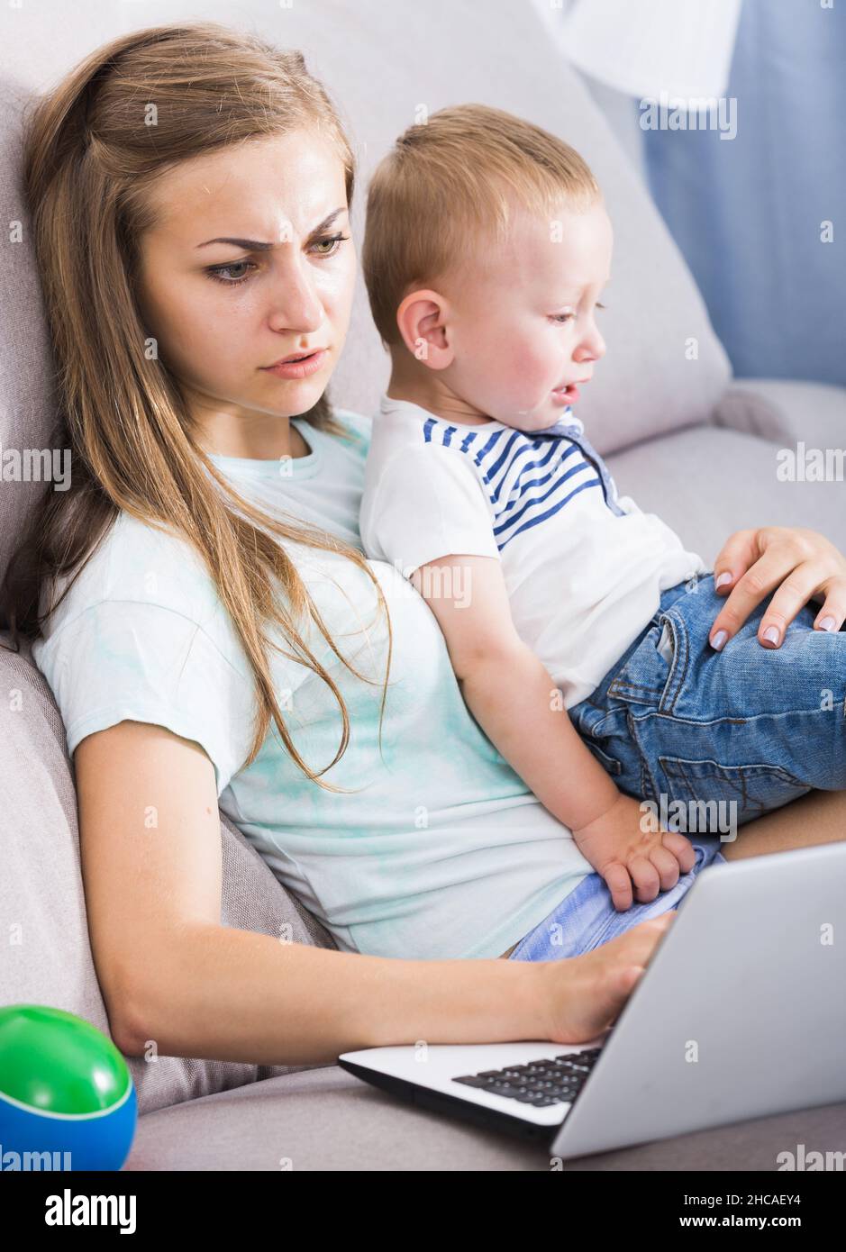 Perplexed female is having issue with work while child crying Stock ...
