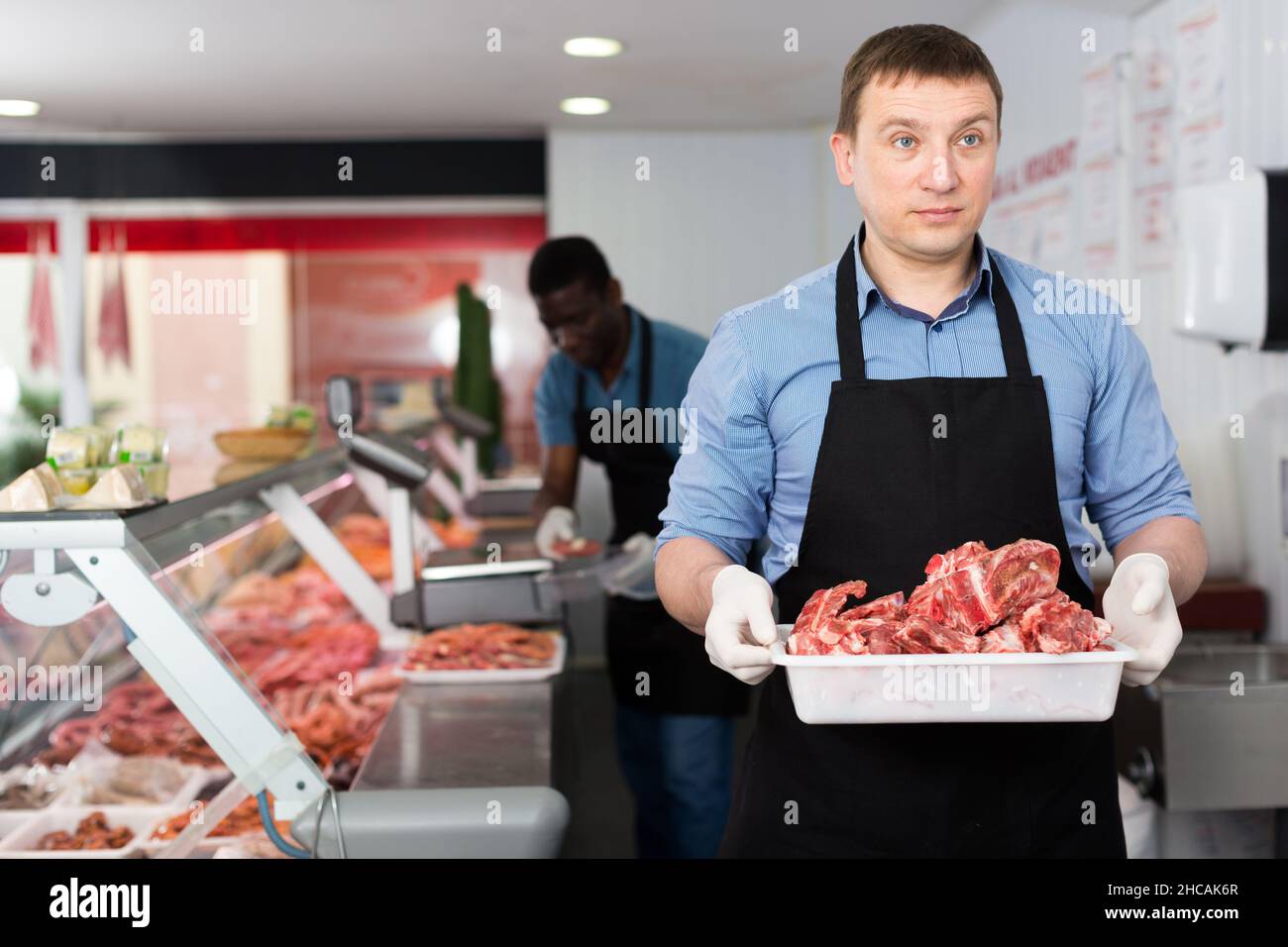 Two butchers arranging meat display Stock Photo - Alamy