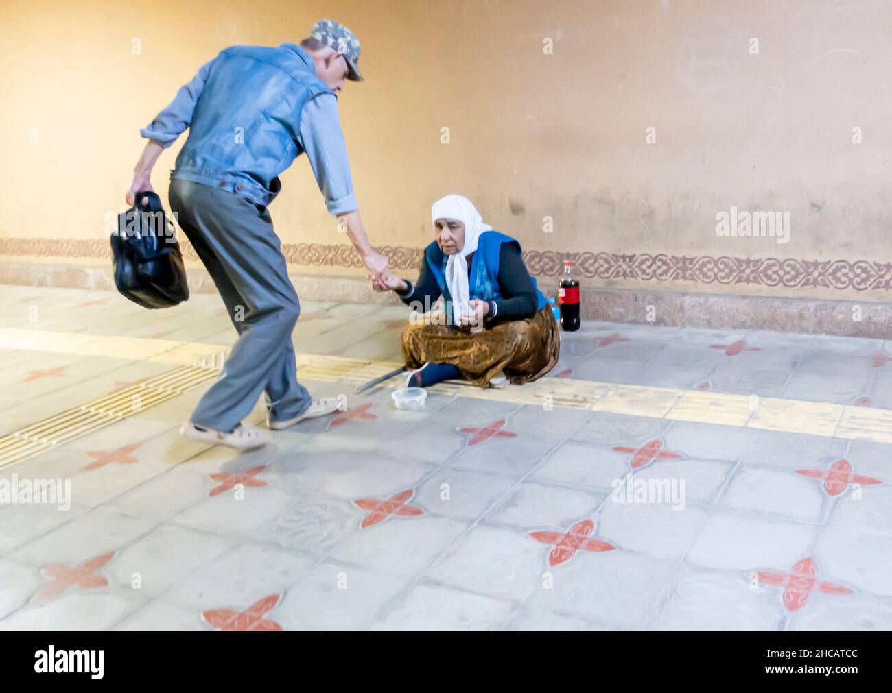 A man giving a female gypsy beggar a change in a street passage in ...