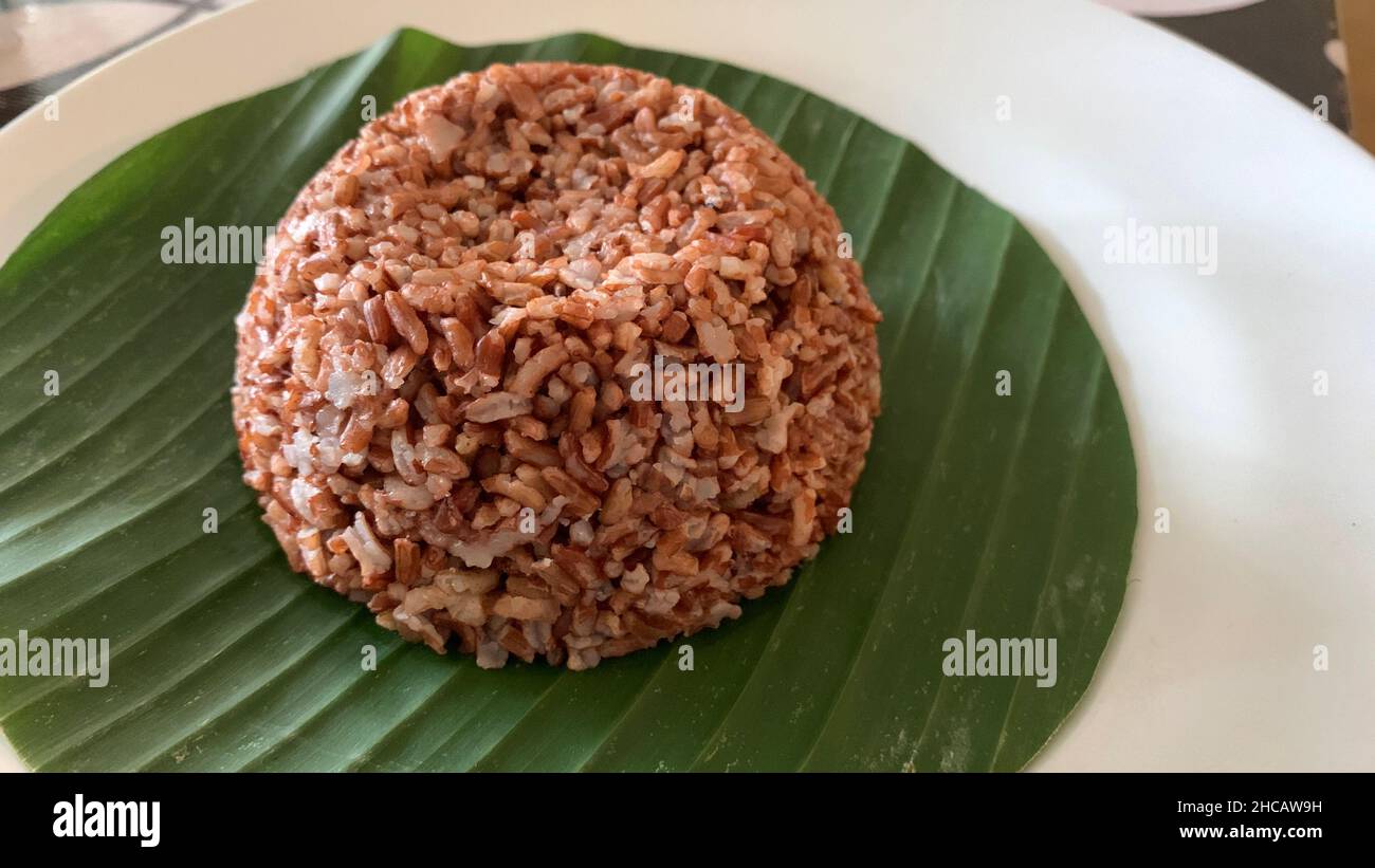 Red rice on banana leaf and plate, ready to eat Stock Photo - Alamy