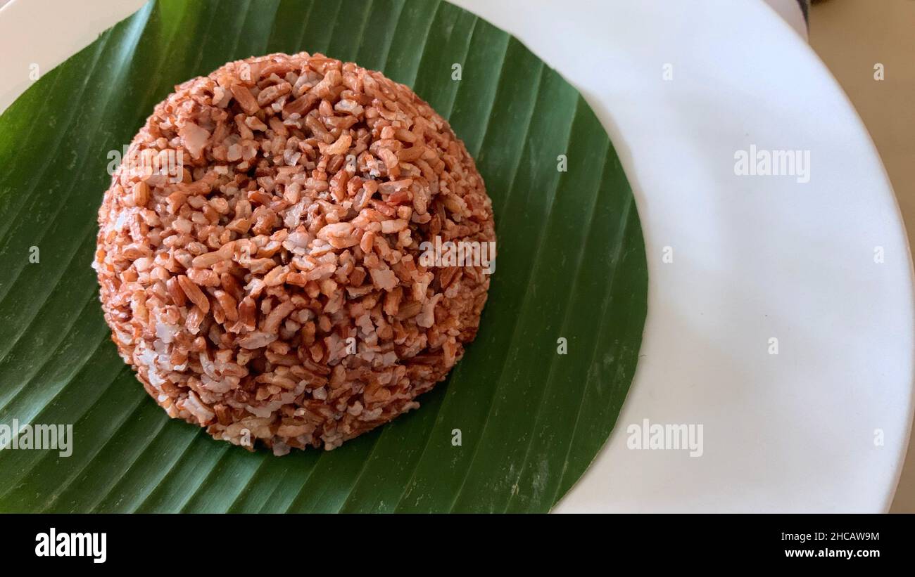 Red rice on banana leaf and plate, ready to eat Stock Photo - Alamy