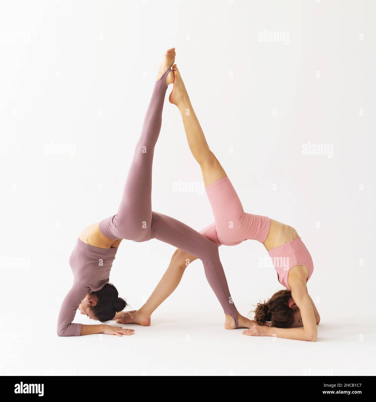 Two Women Practicing Yoga Performing The Paired Exercise Of Eka Pada