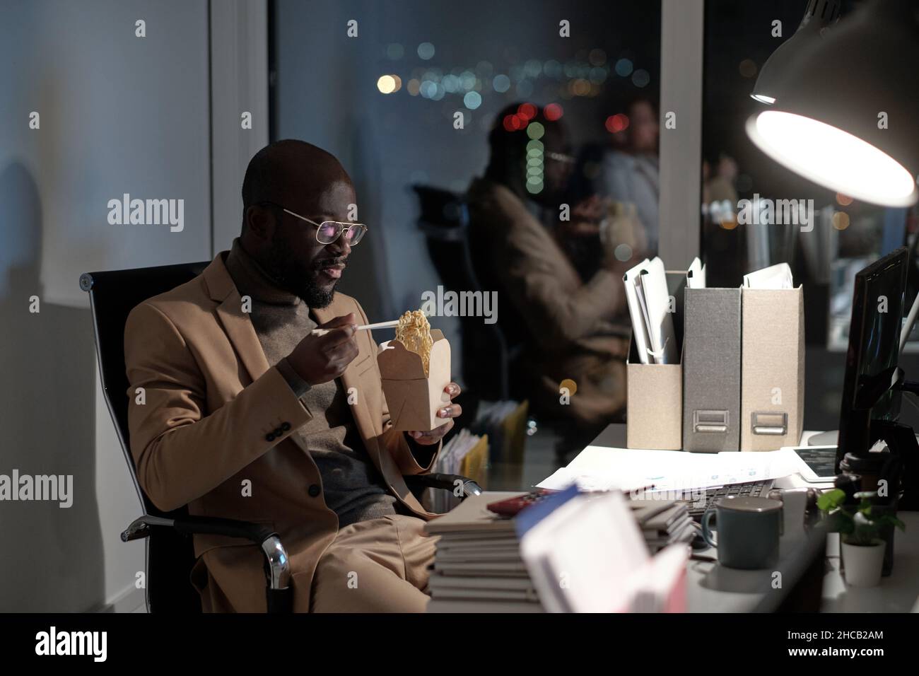 Hungry young businessman with chopsticks and box of chinese wok sitting ...