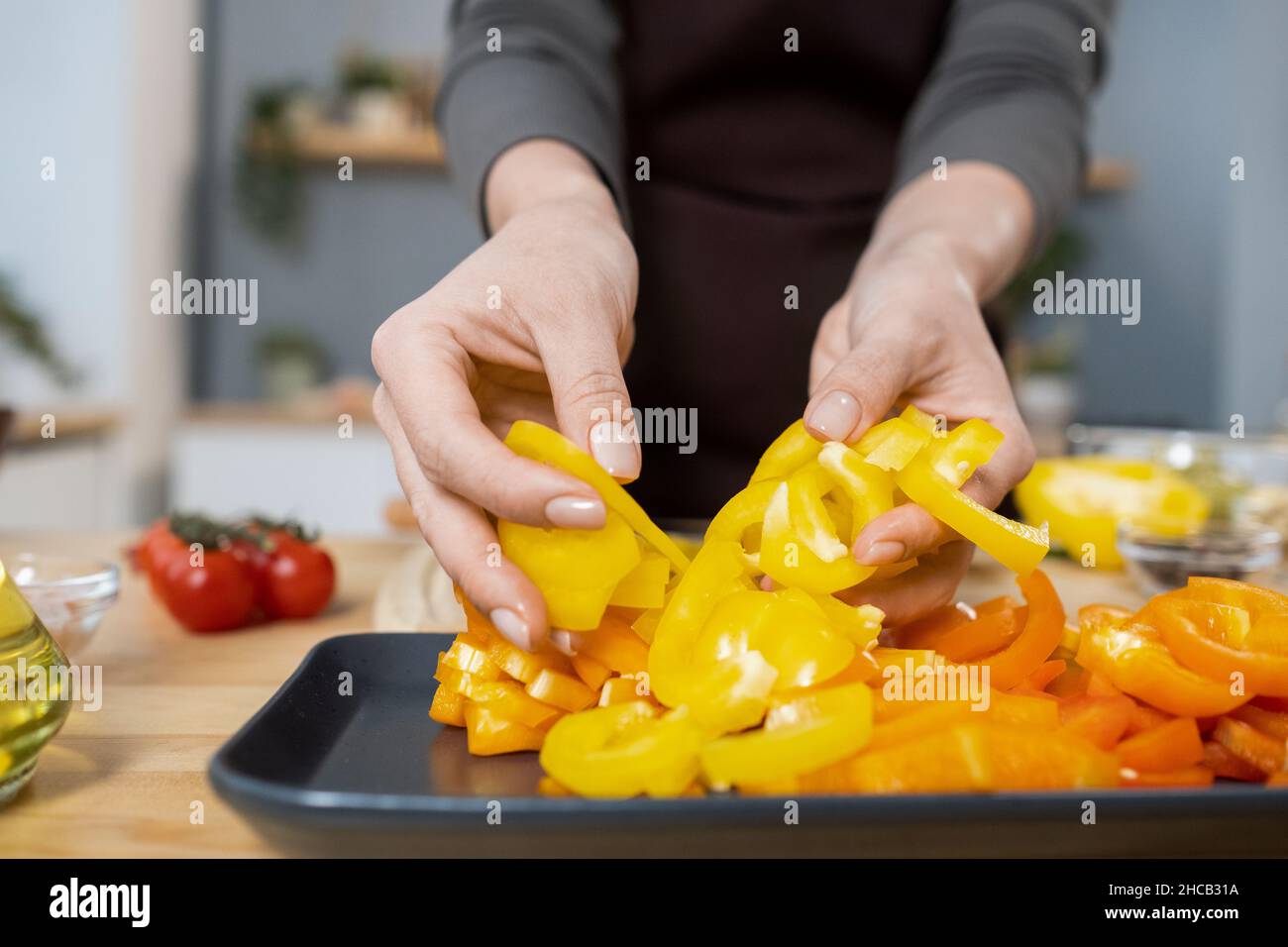 Hands of female putting chopped fresh yellow capsicum on tray while ...