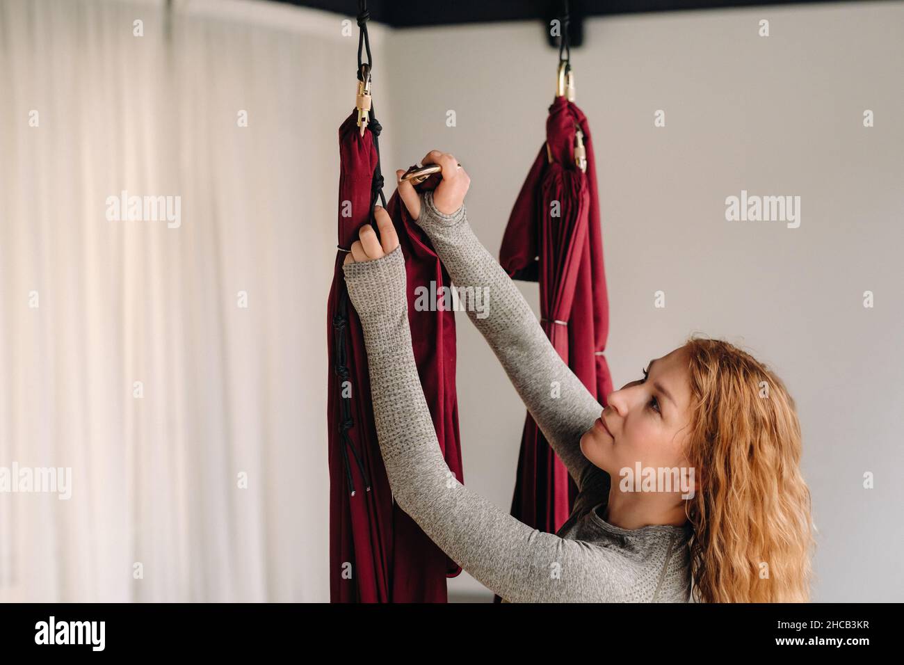 A woman fastens a hook from a hanging hammock for yoga in the gym Stock ...