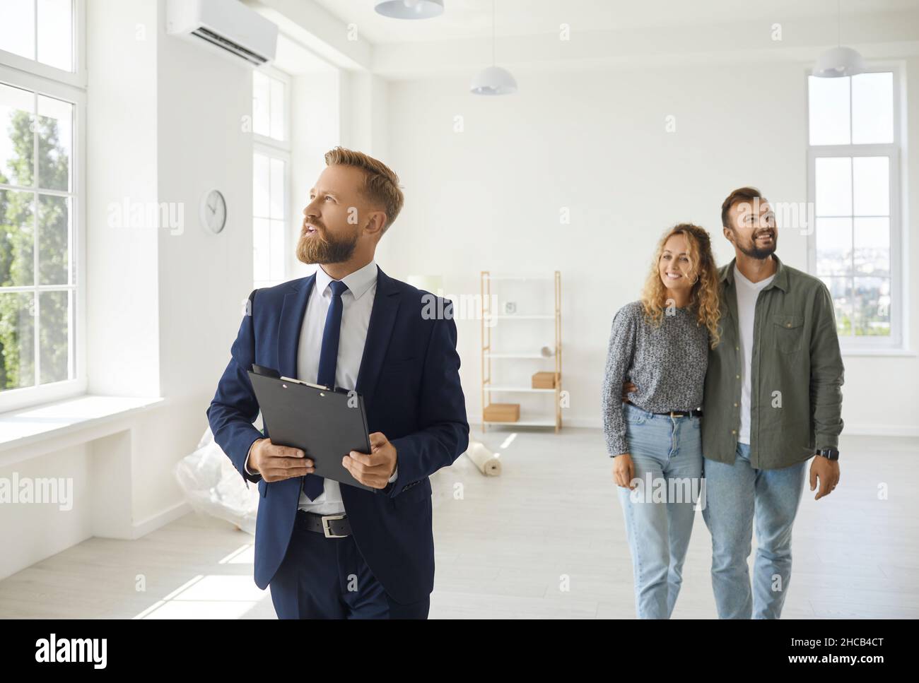 Professional real estate agent giving a happy young couple a tour about ...
