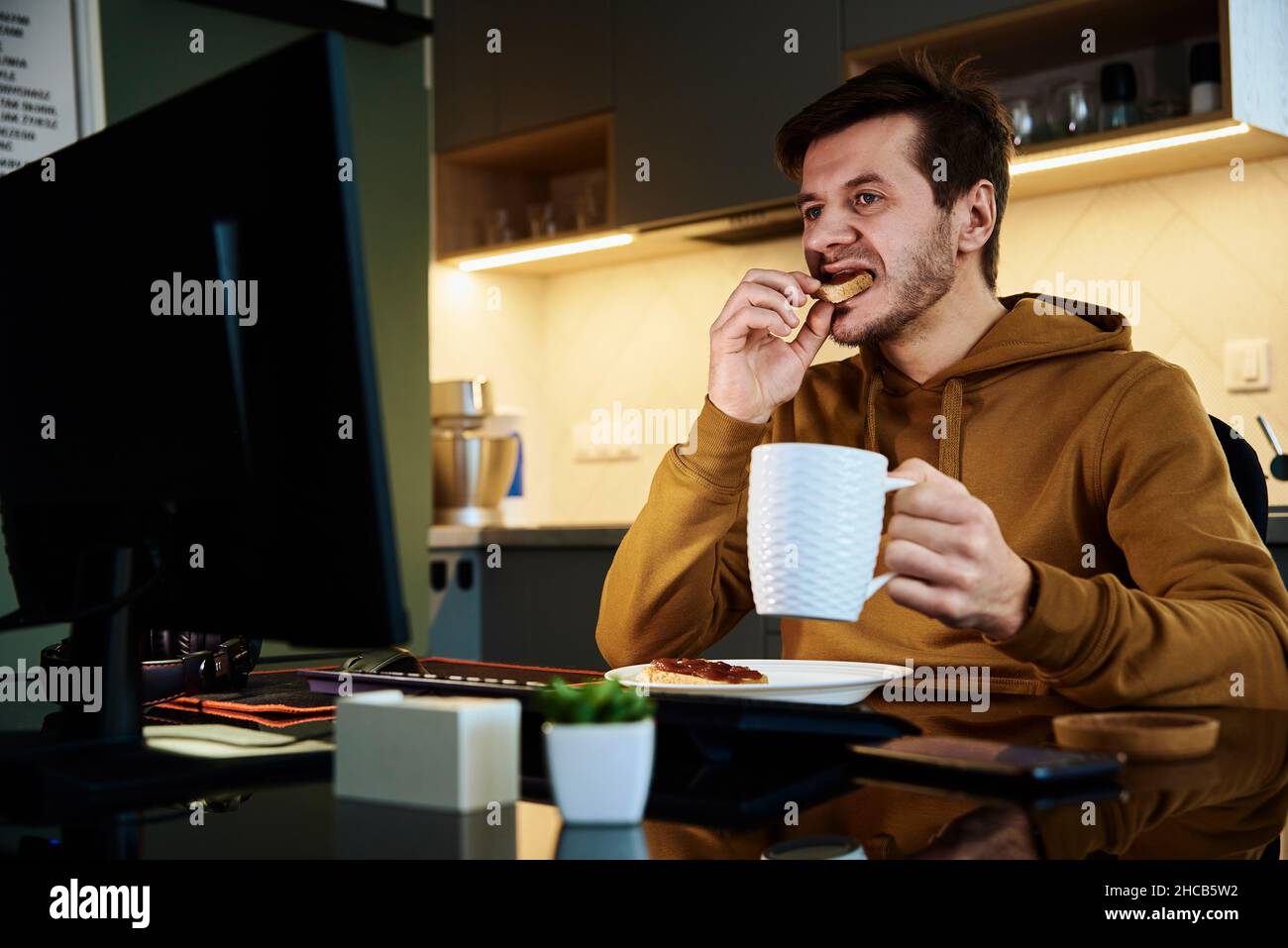 Man works at home office workplace eating while works at computer ...