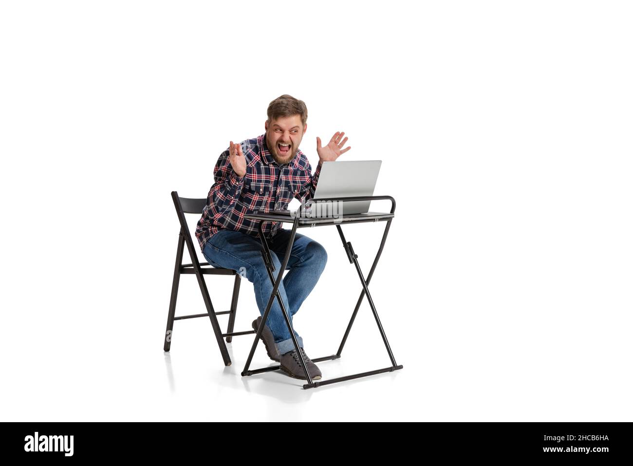 Full-length portrait of man screaming into laptop screen, having online ...