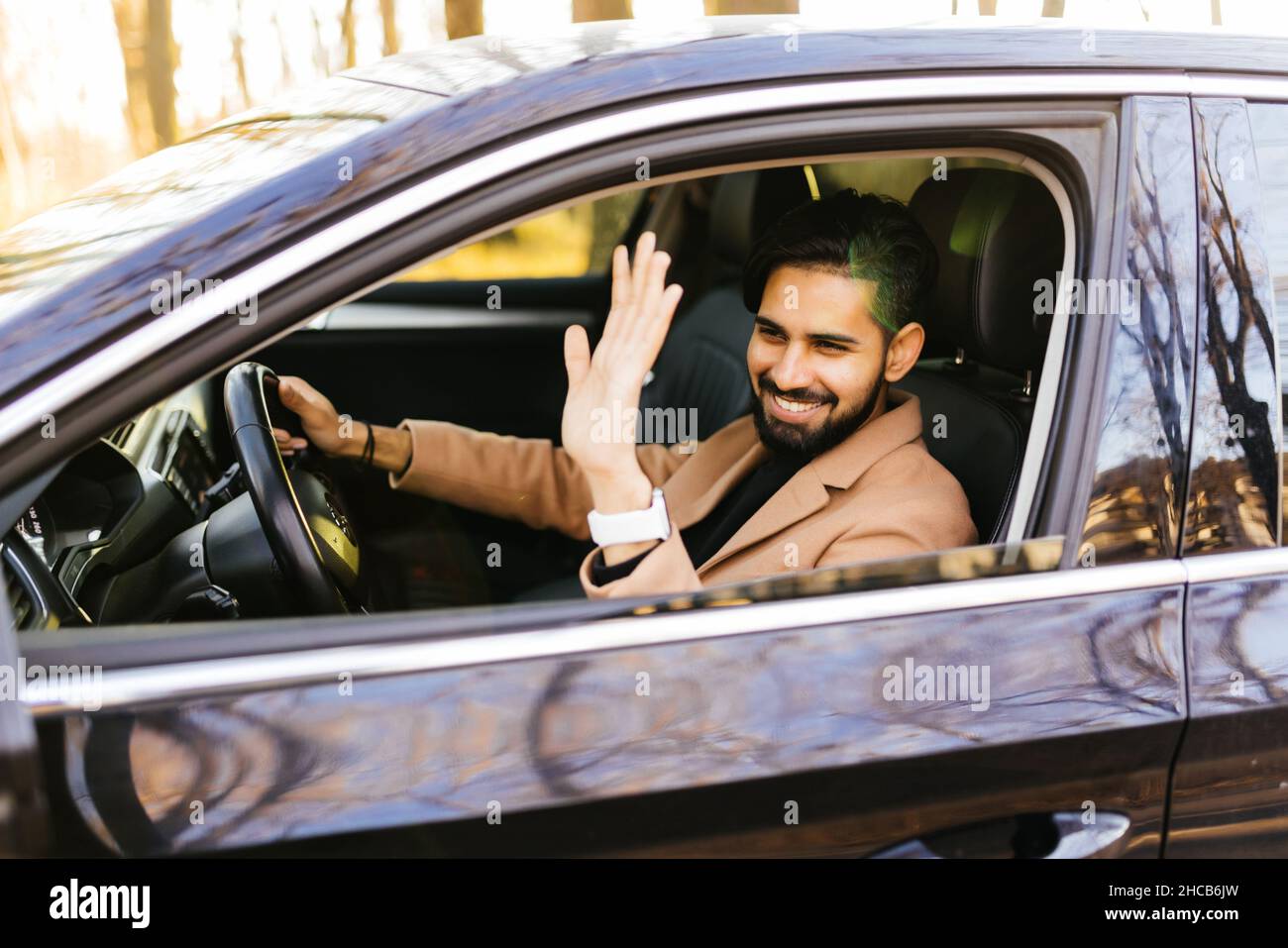 Young happy man driving car and waving hand Stock Photo - Alamy