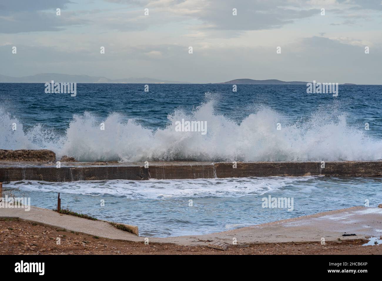 Breaking waves on the dock of Saronida's little fihinh harbour, Greece ...