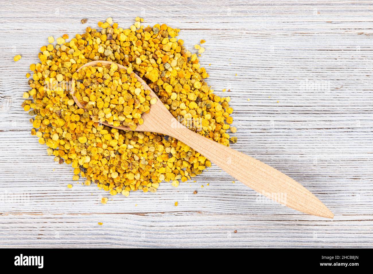 top view of wooden spoon in pile of natural bee pollen on gray wood ...