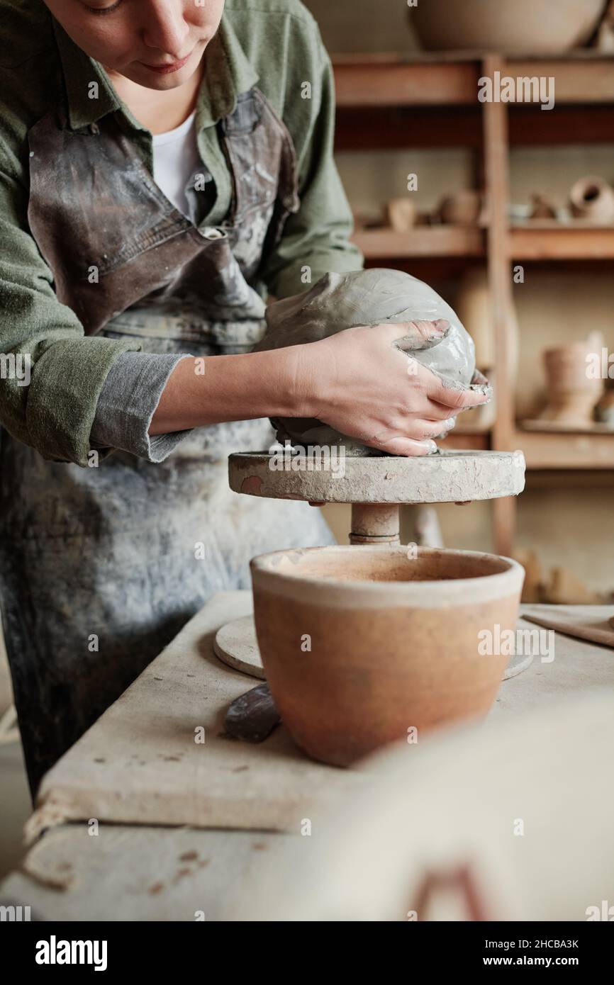 Close-up of worker making form of future vase from piece of clay ...