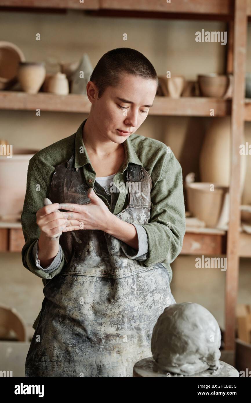 Female pottery artist working on pottery wheel with piece of clay, she ...