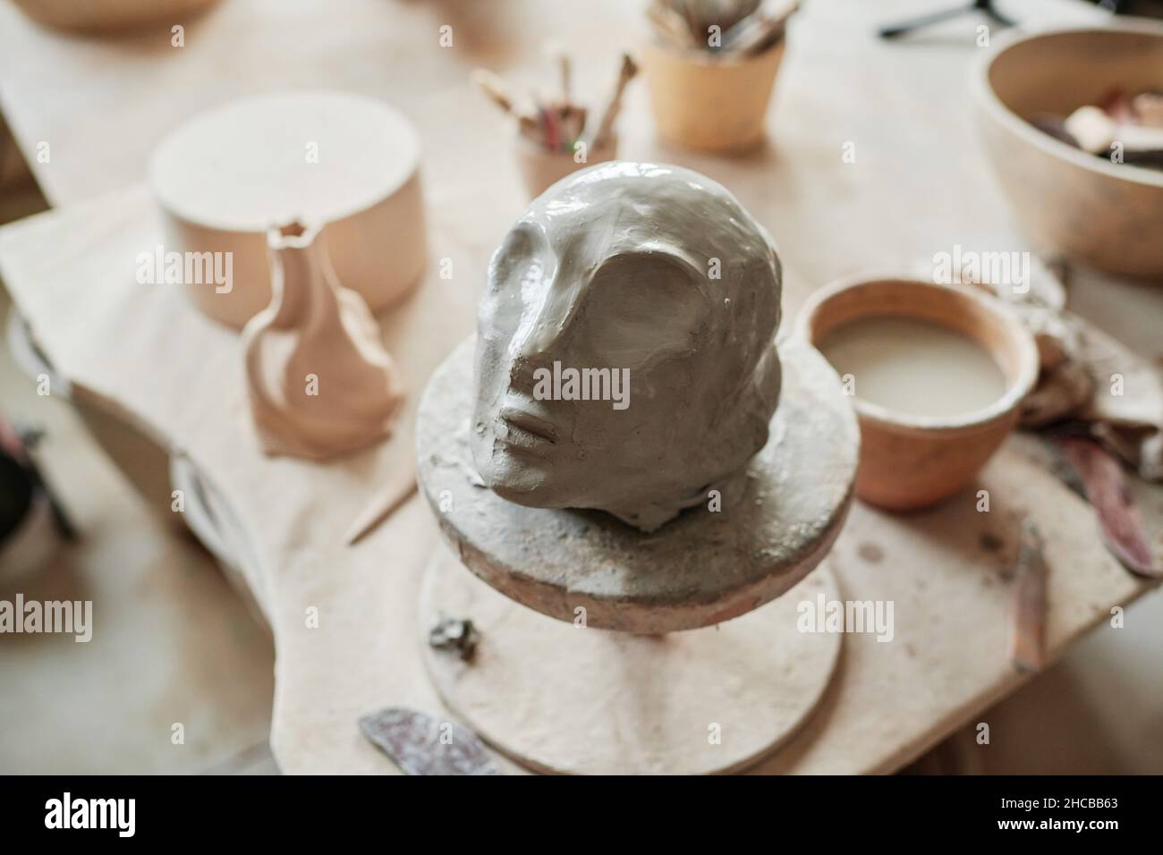 Close-up of clay sculpture of human face on pottery wheel in workshop ...