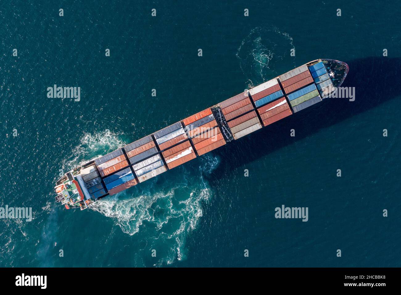 Sea container ship is moving at sea. Around the foam from the work of ...