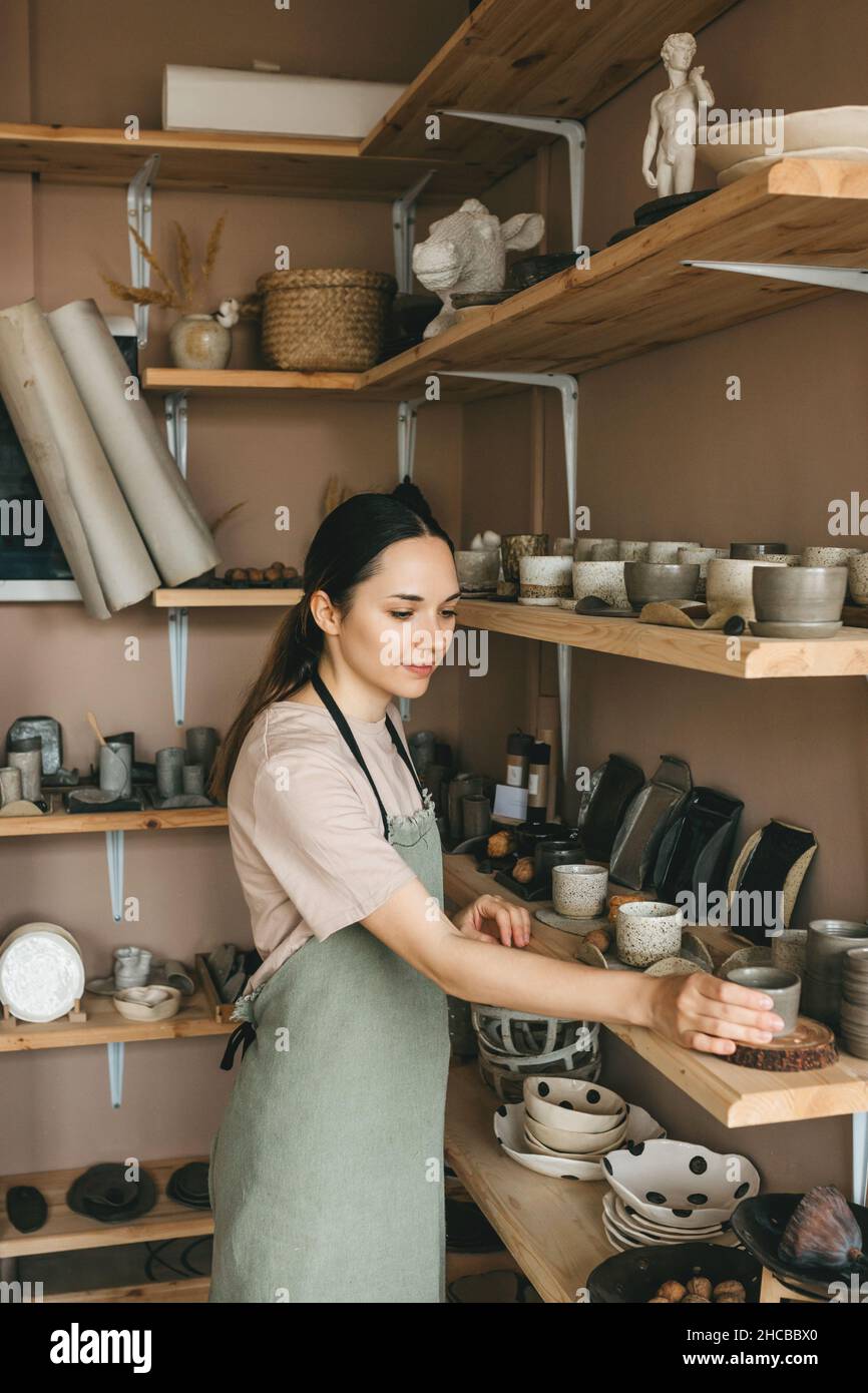 Young woman sells handmade pottery in a store. Workshop production in ...