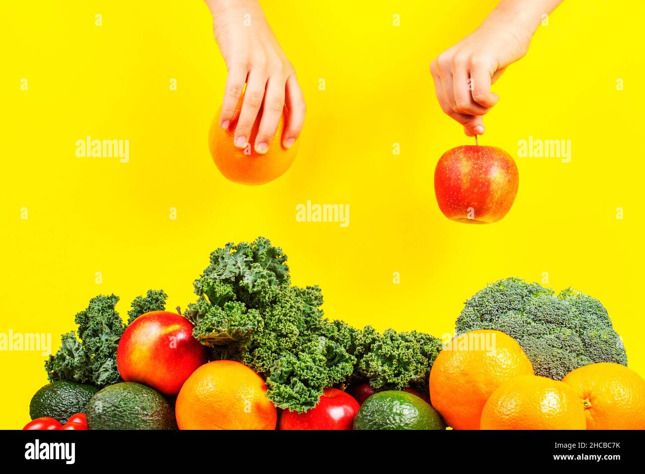 Hands picking apple and orange fruit from pile of fresh vegetables and ...