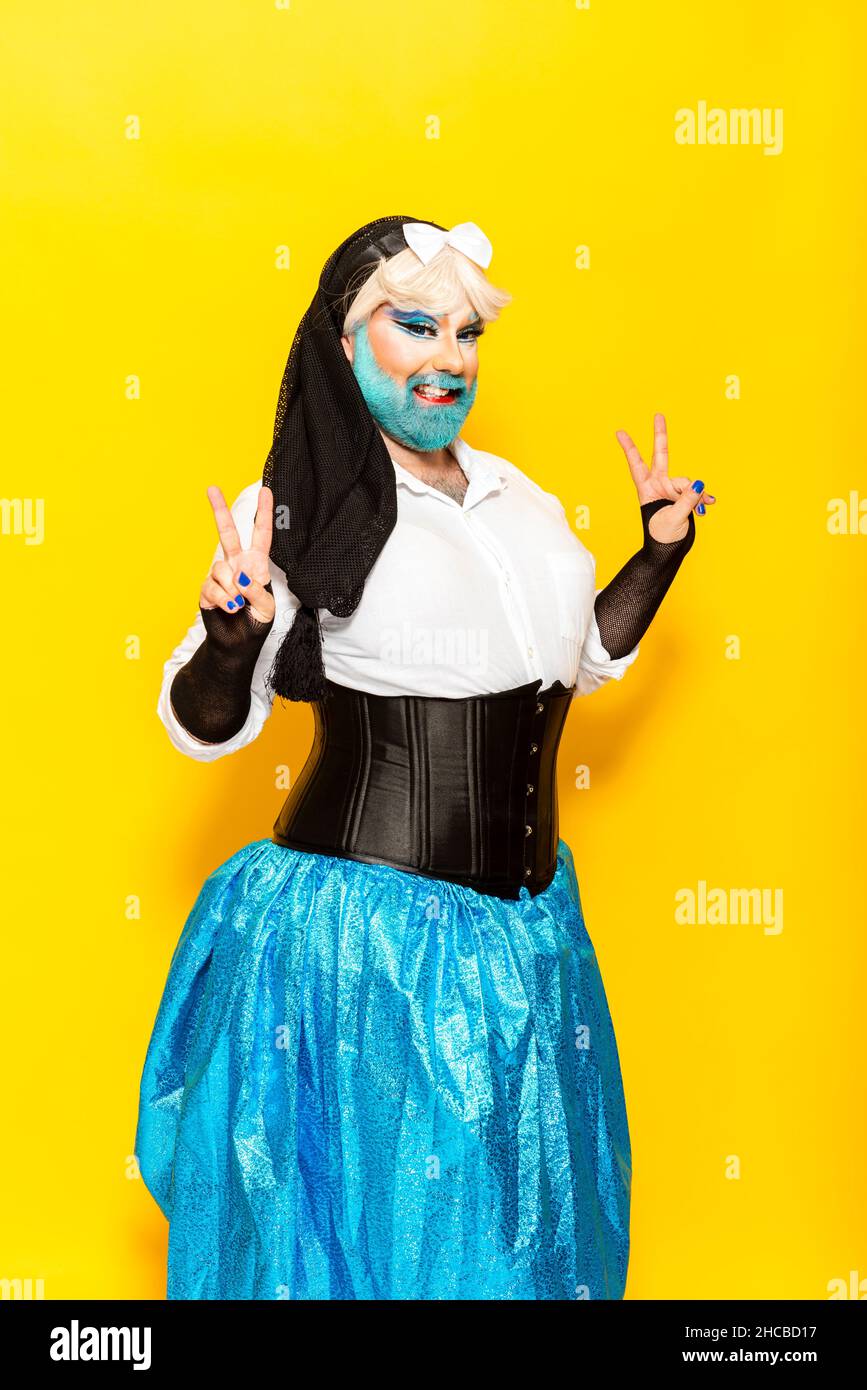 Drag queen with hand on hip holding red fan against yellow background ...