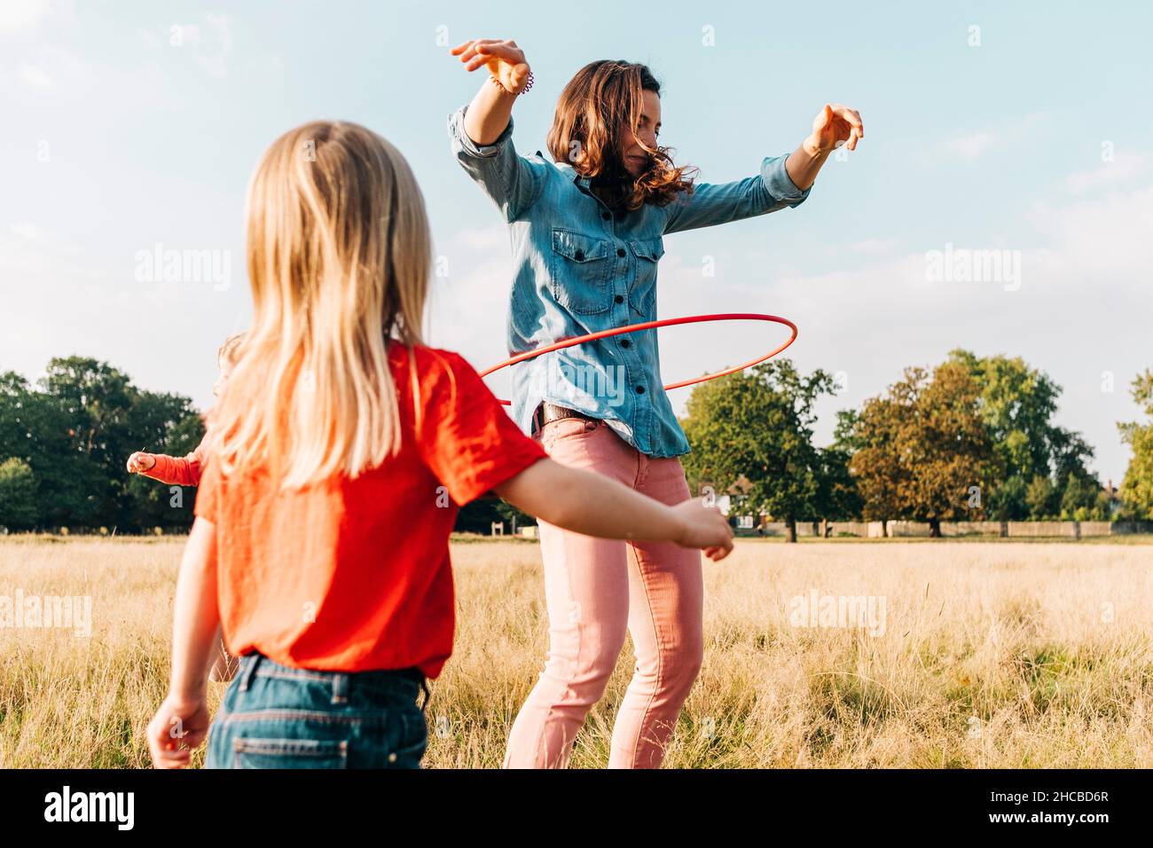 Mother spinning hula hoop by daughter in park Stock Photo - Alamy