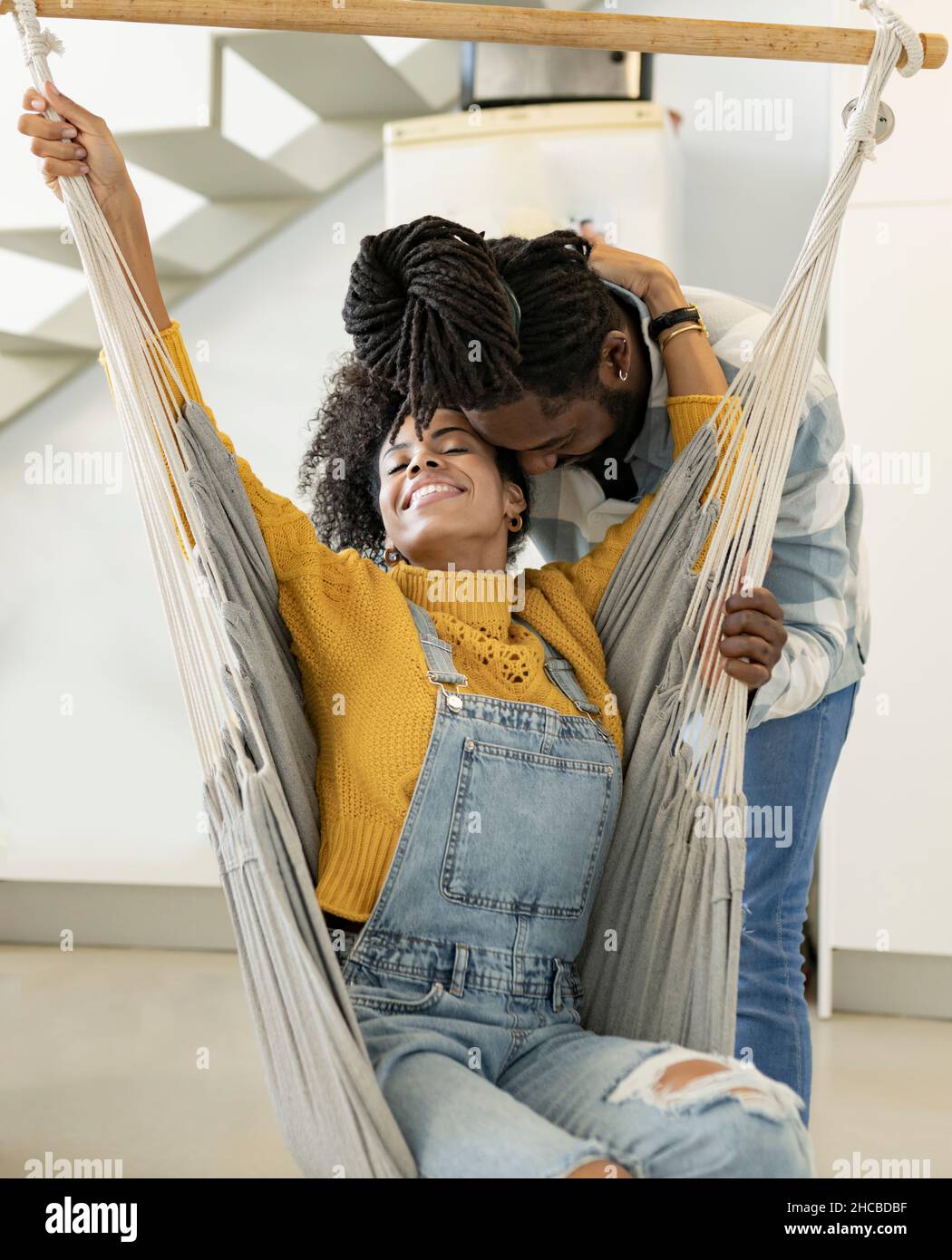 Happy hipster man filming with girlfriend embracing in living room ...