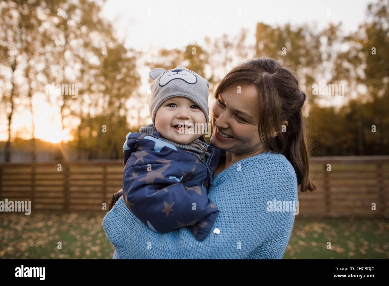Mother carrying cheerful baby boy at lawn Stock Photo - Alamy