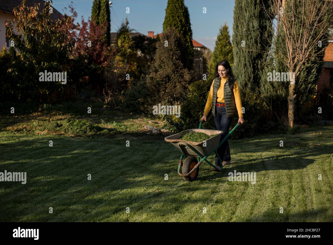 Woman walking with wheelbarrow at backyard Stock Photo - Alamy