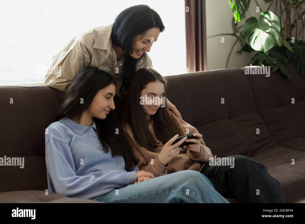 Mother and daughters using mobile phone at home Stock Photo - Alamy