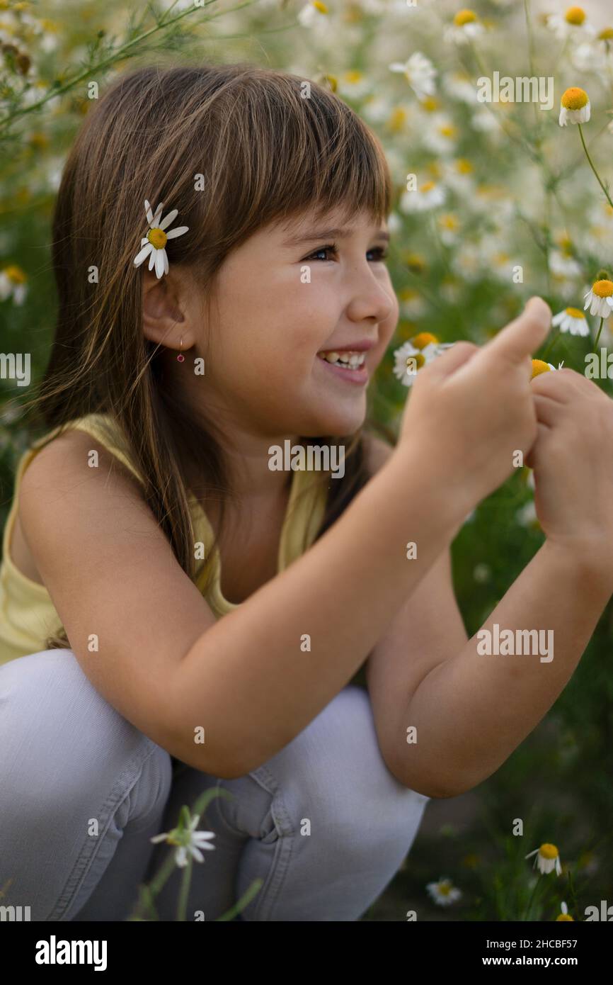 Smiling cute girl crouching in meadow Stock Photo - Alamy