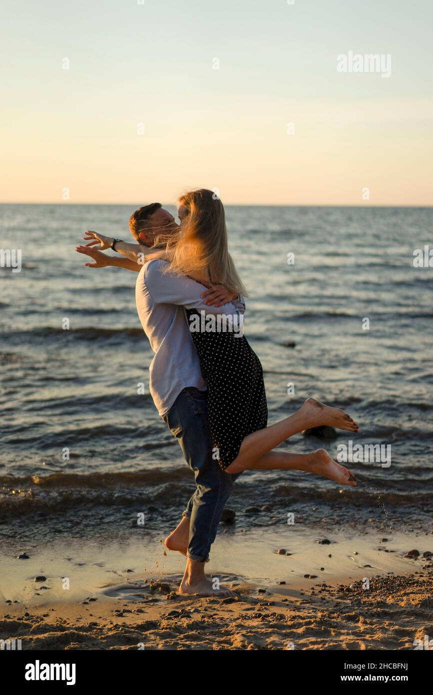 Playful man picking up woman at water's edge Stock Photo - Alamy
