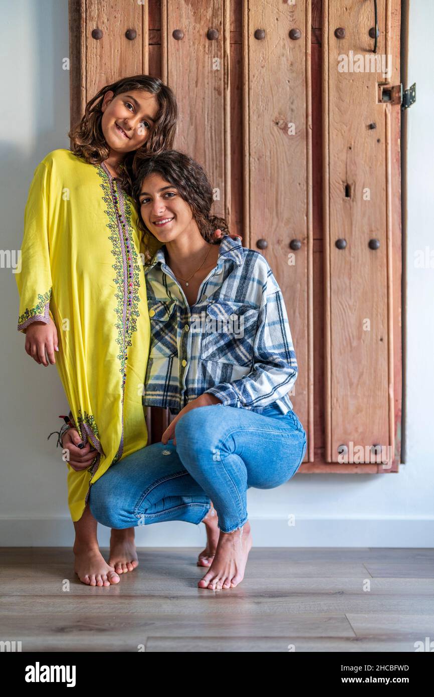 Happy sisters embracing each other in front of door Stock Photo - Alamy