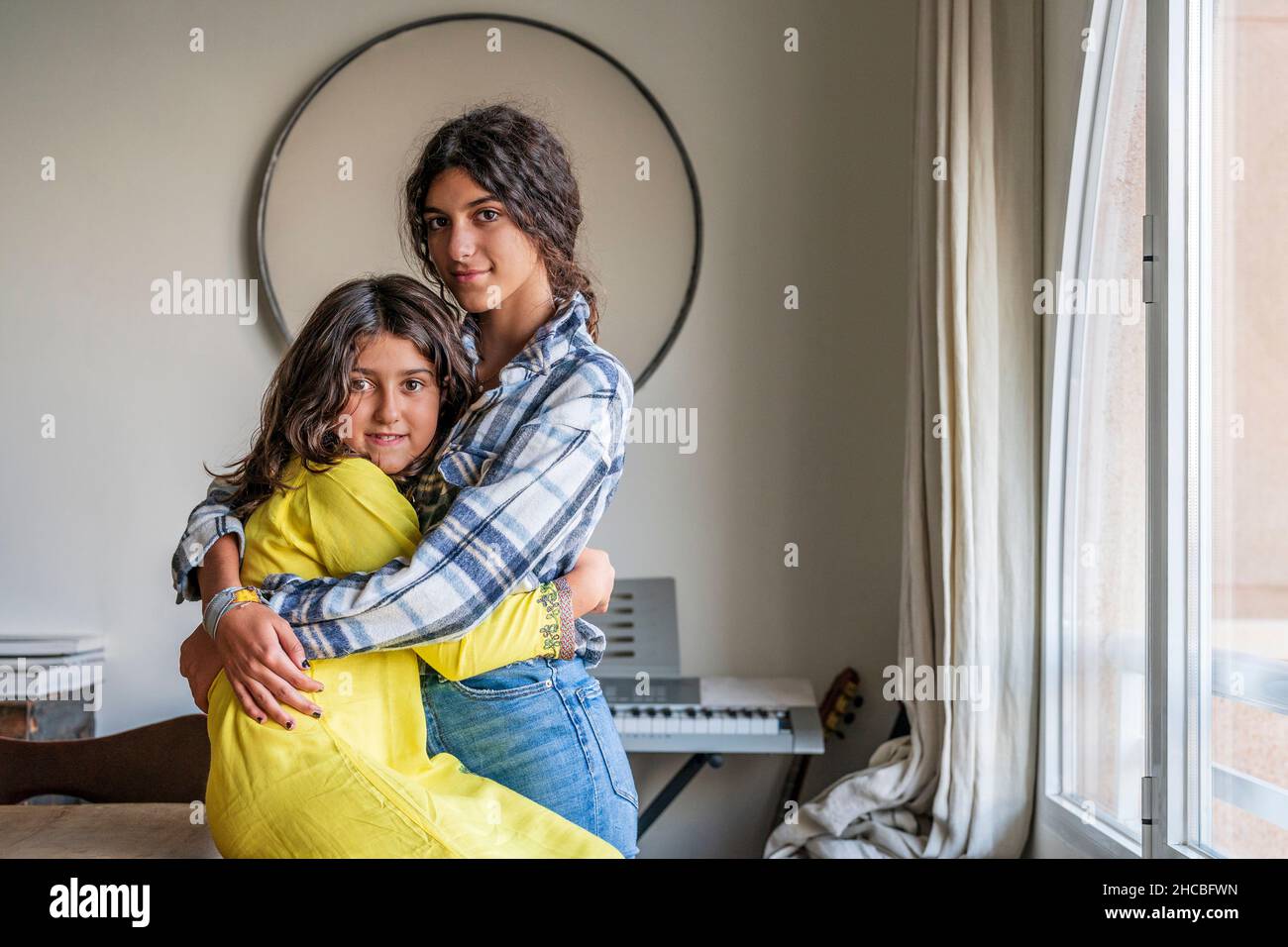 Sisters hugging each other at home Stock Photo - Alamy