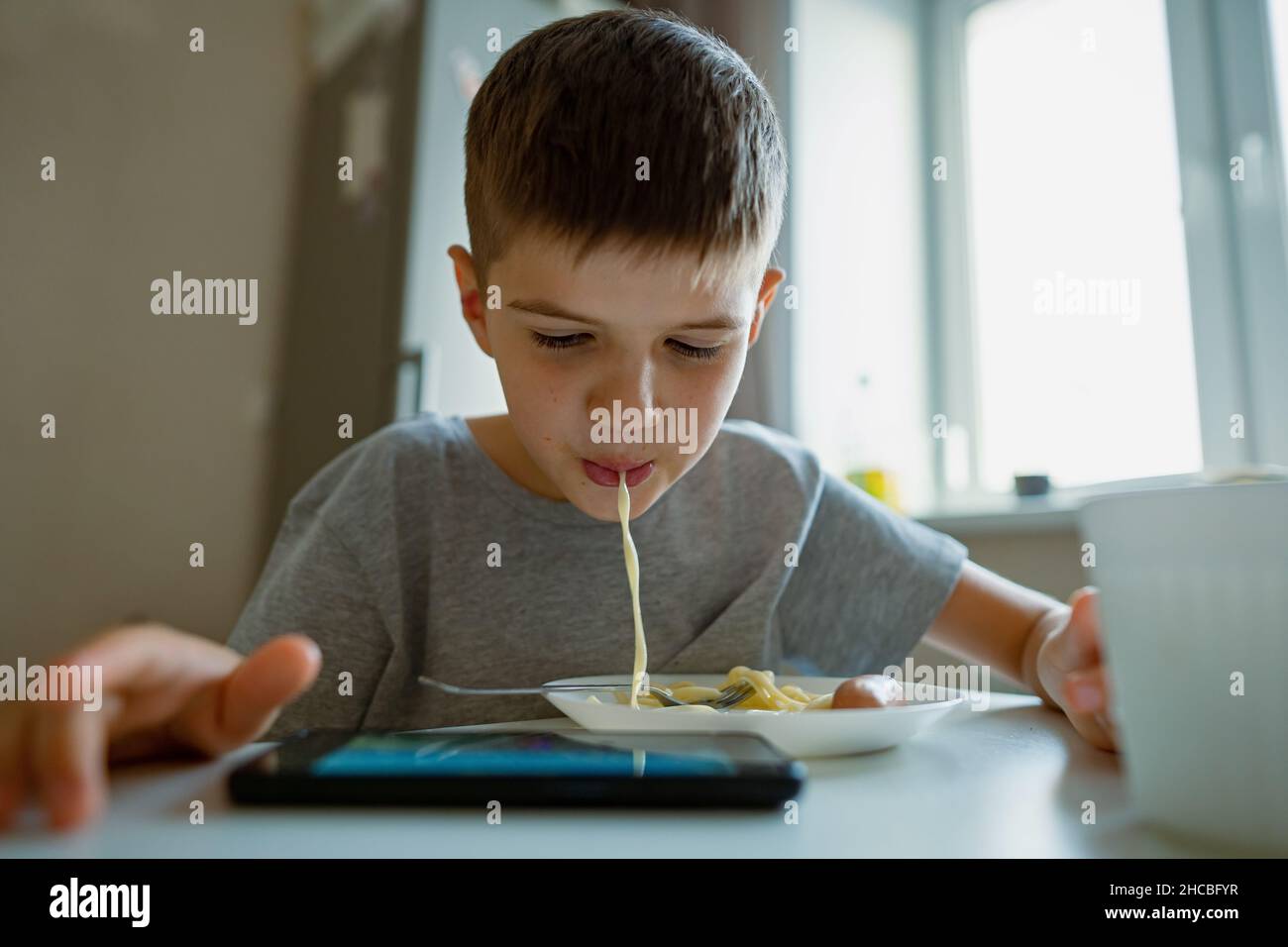 Boy, child eats pasta sucking long pasta into his mouth Stock Photo - Alamy