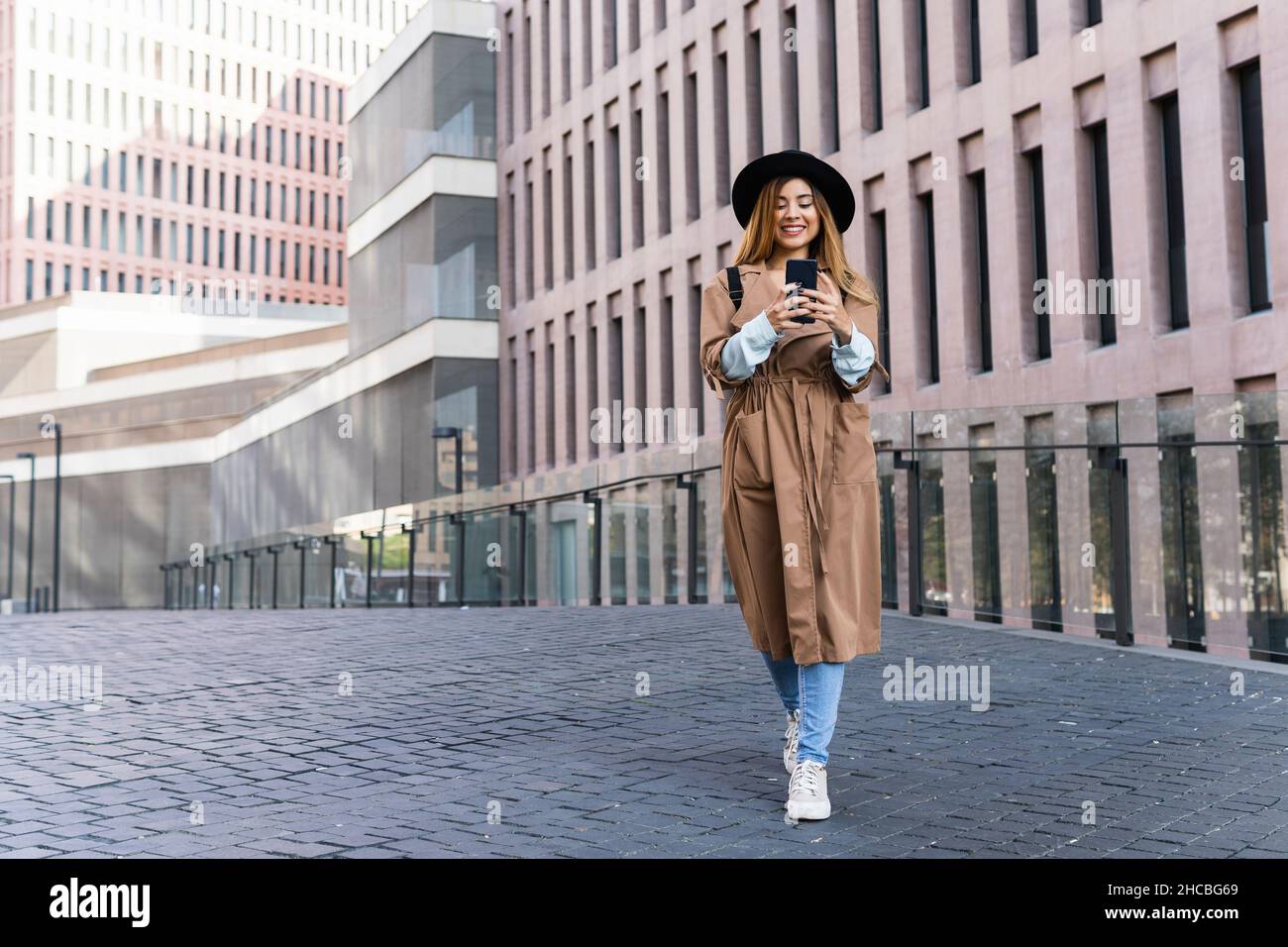Fashionable woman walking using smartphone hi-res stock photography and ...