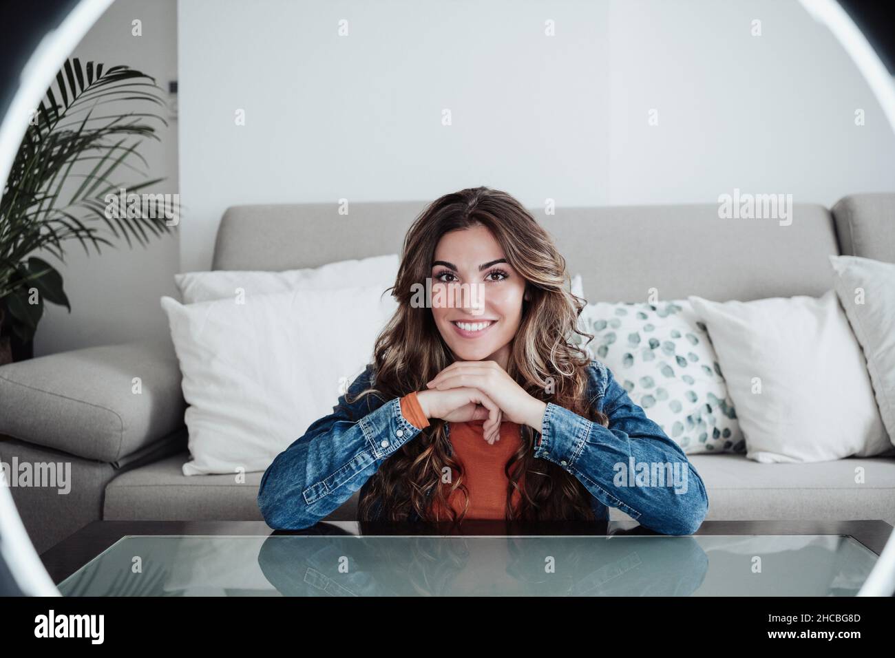 Smiling beautiful vlogger seen through ring light at home studio Stock ...