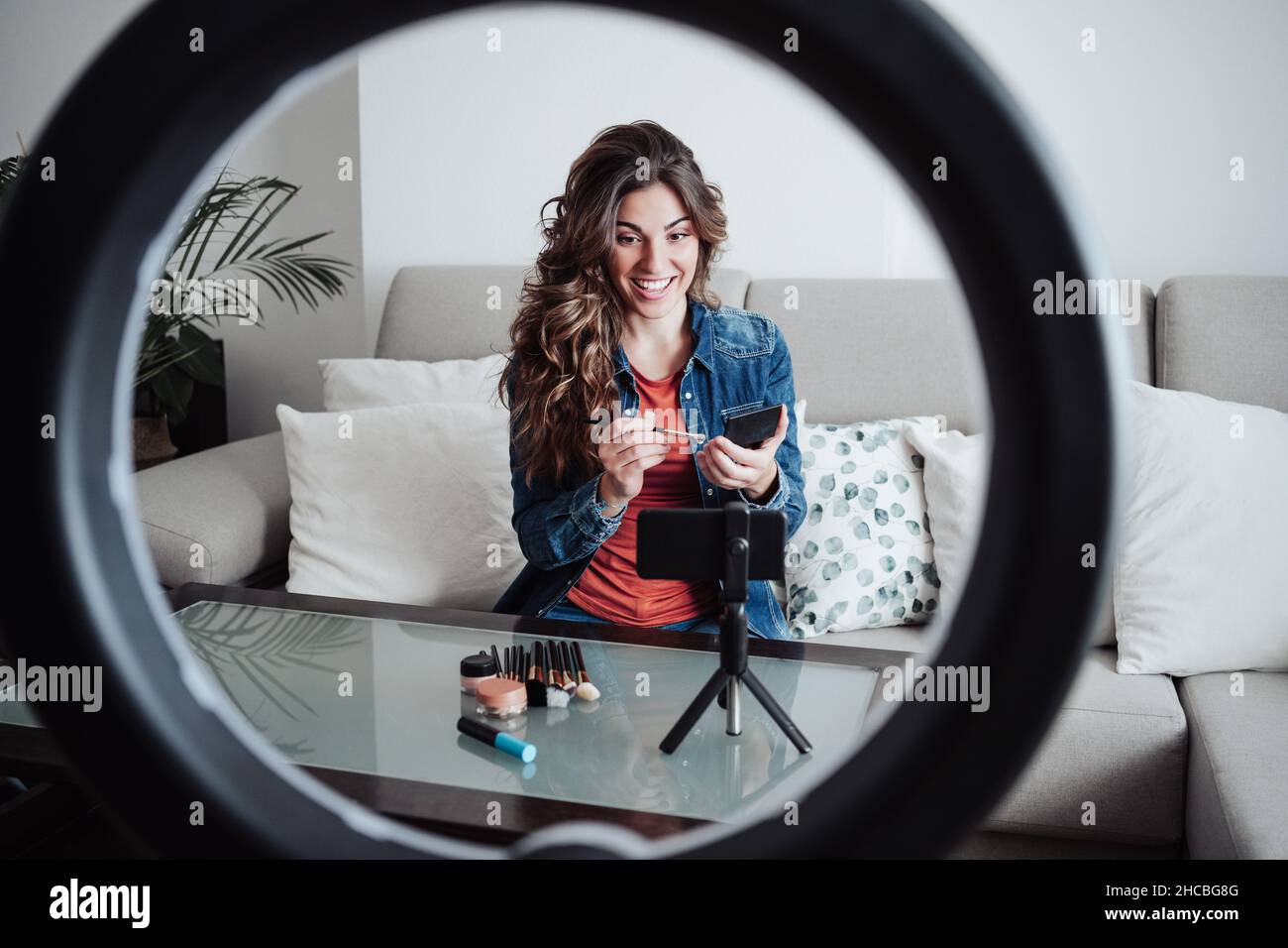 Smiling influencer with make-up palette influencing at home studio ...