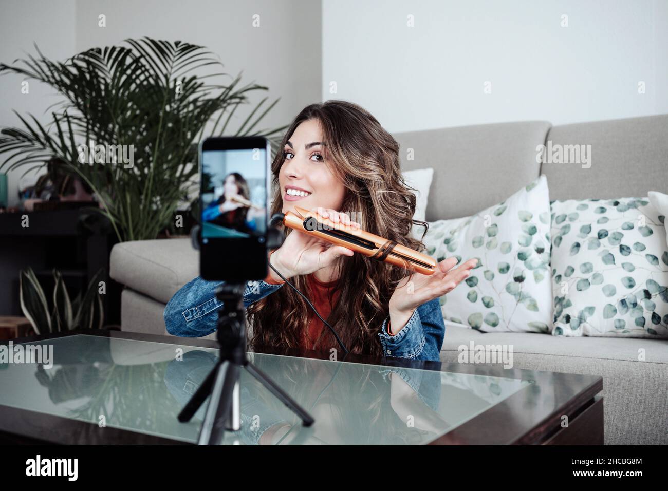 Young vlogger filming tutorial with hair straightener at home Stock ...