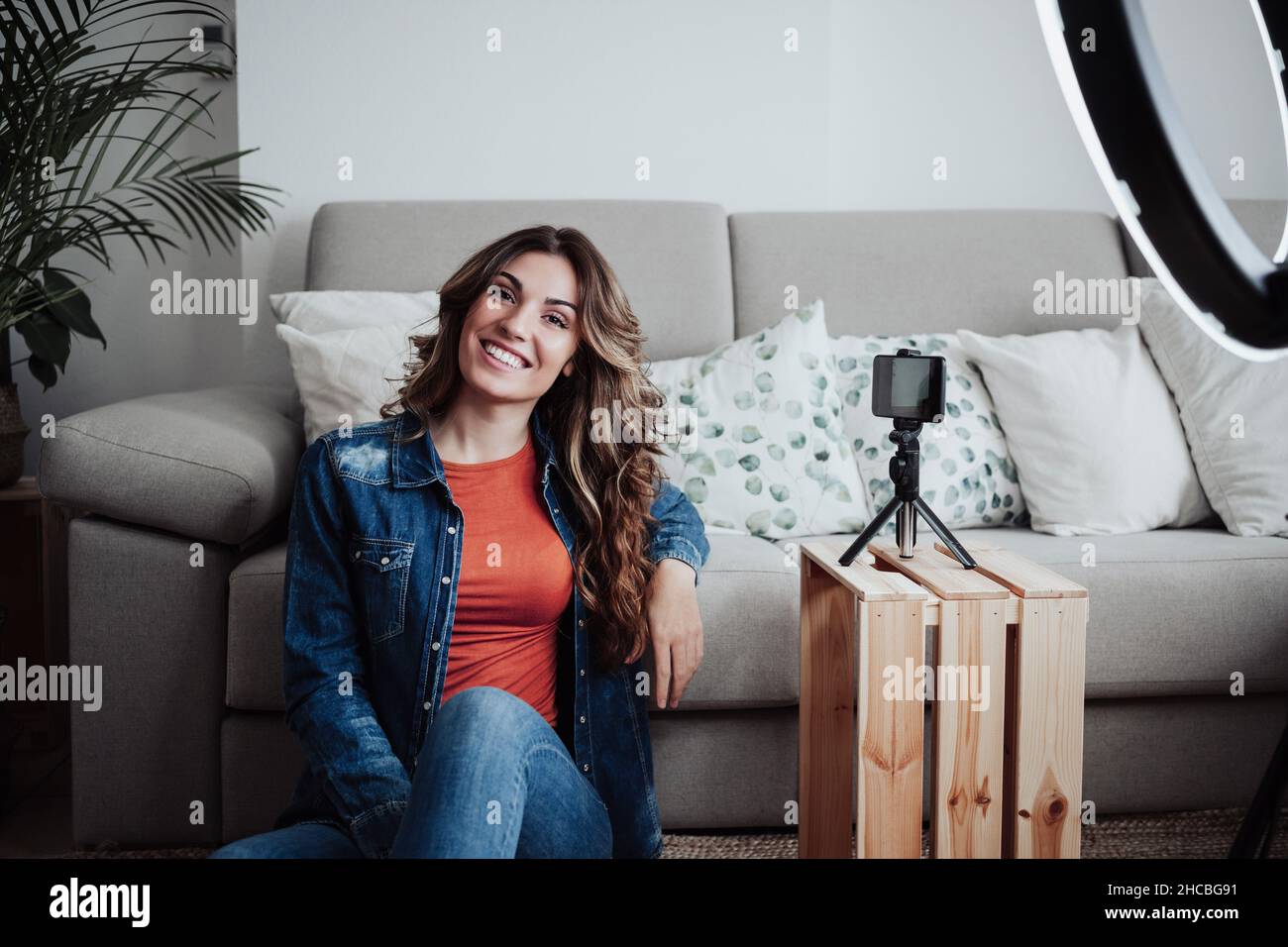 Beautiful vlogger smiling at sofa in home studio Stock Photo - Alamy