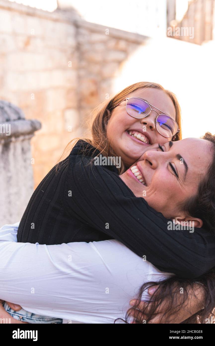 Smiling mother and daughter making mustache with hair on bench Stock ...