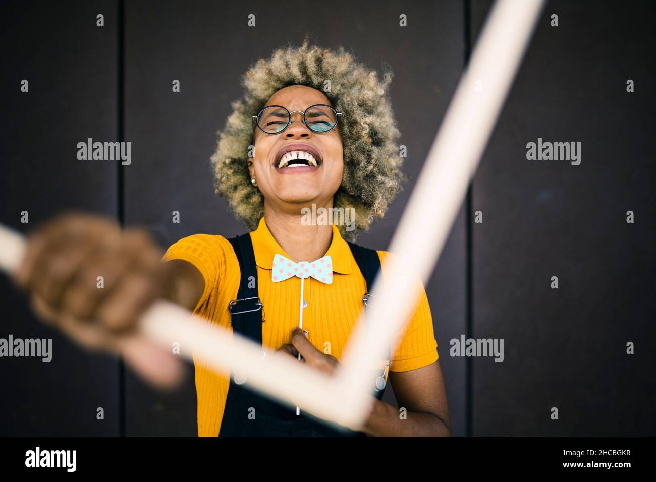 Cheerful woman holding bow tie and frame in front of wall Stock Photo ...