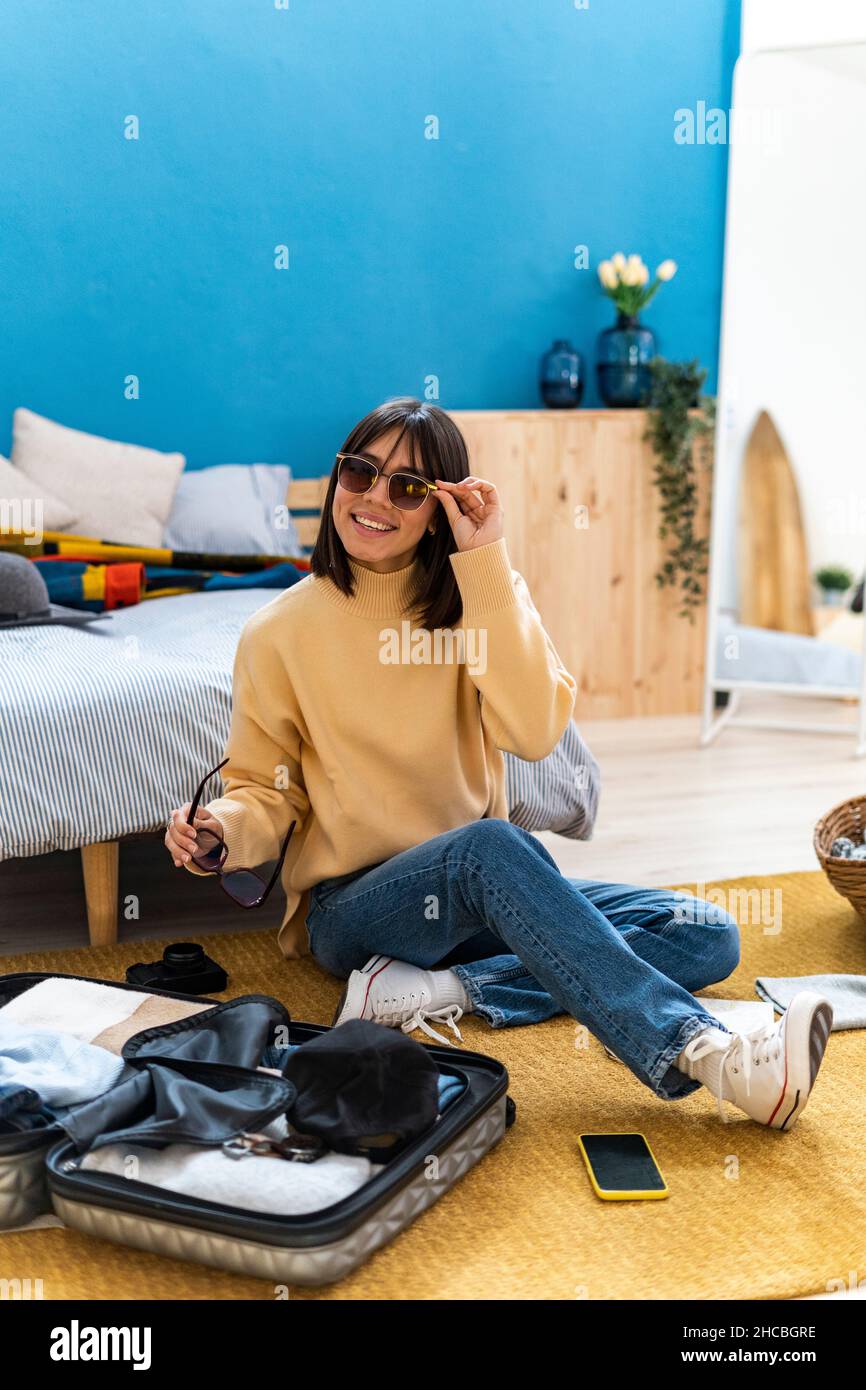 Happy young woman packing suitcase in bedroom Stock Photo - Alamy
