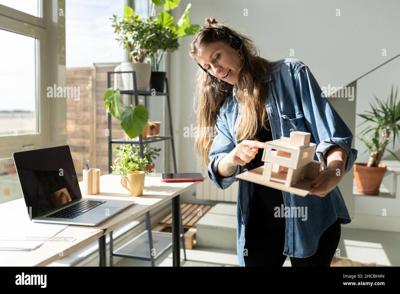 Female architect showing architectural model on video conference ...